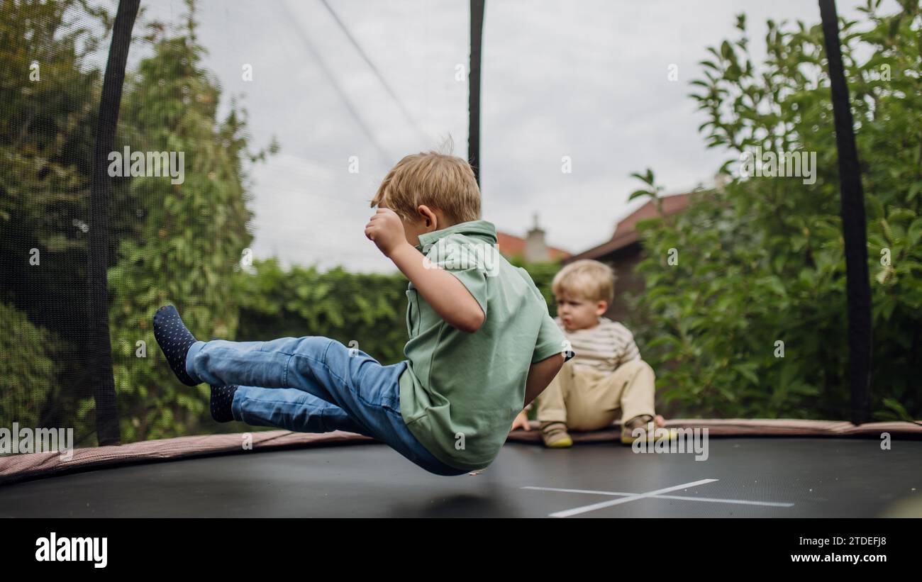Little boys, brothers jumping on trampoline in the backyard, doing ...
