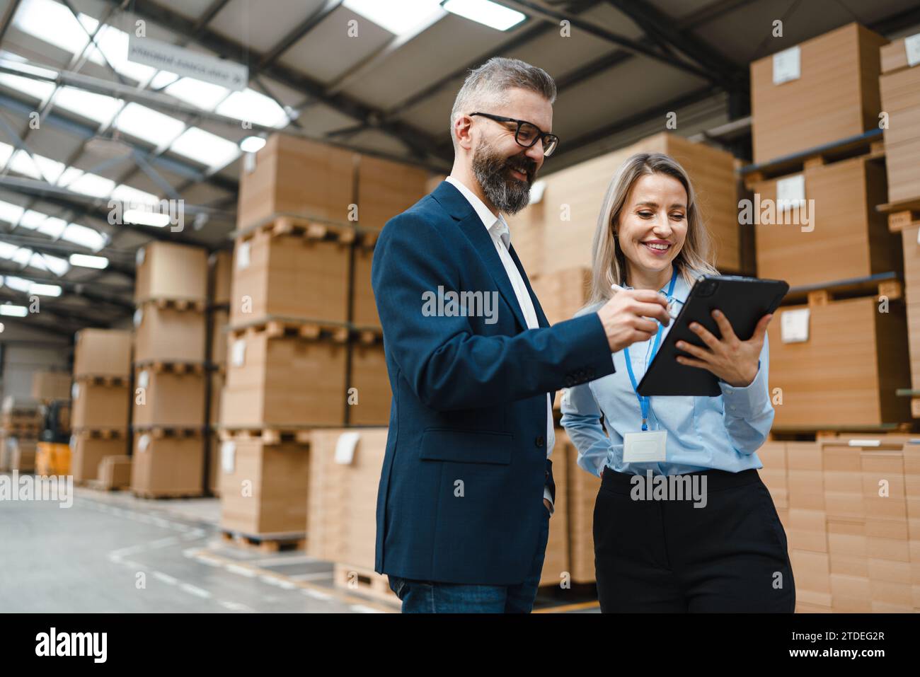 Female warehouse manager talking with logistics employee in warehouse ...