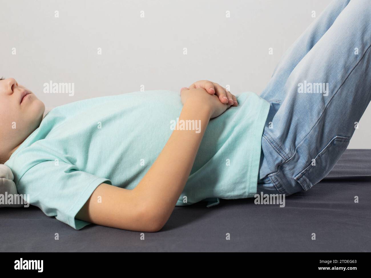 A seven-year-old girl lies and holds her lower abdomen with pain and ...