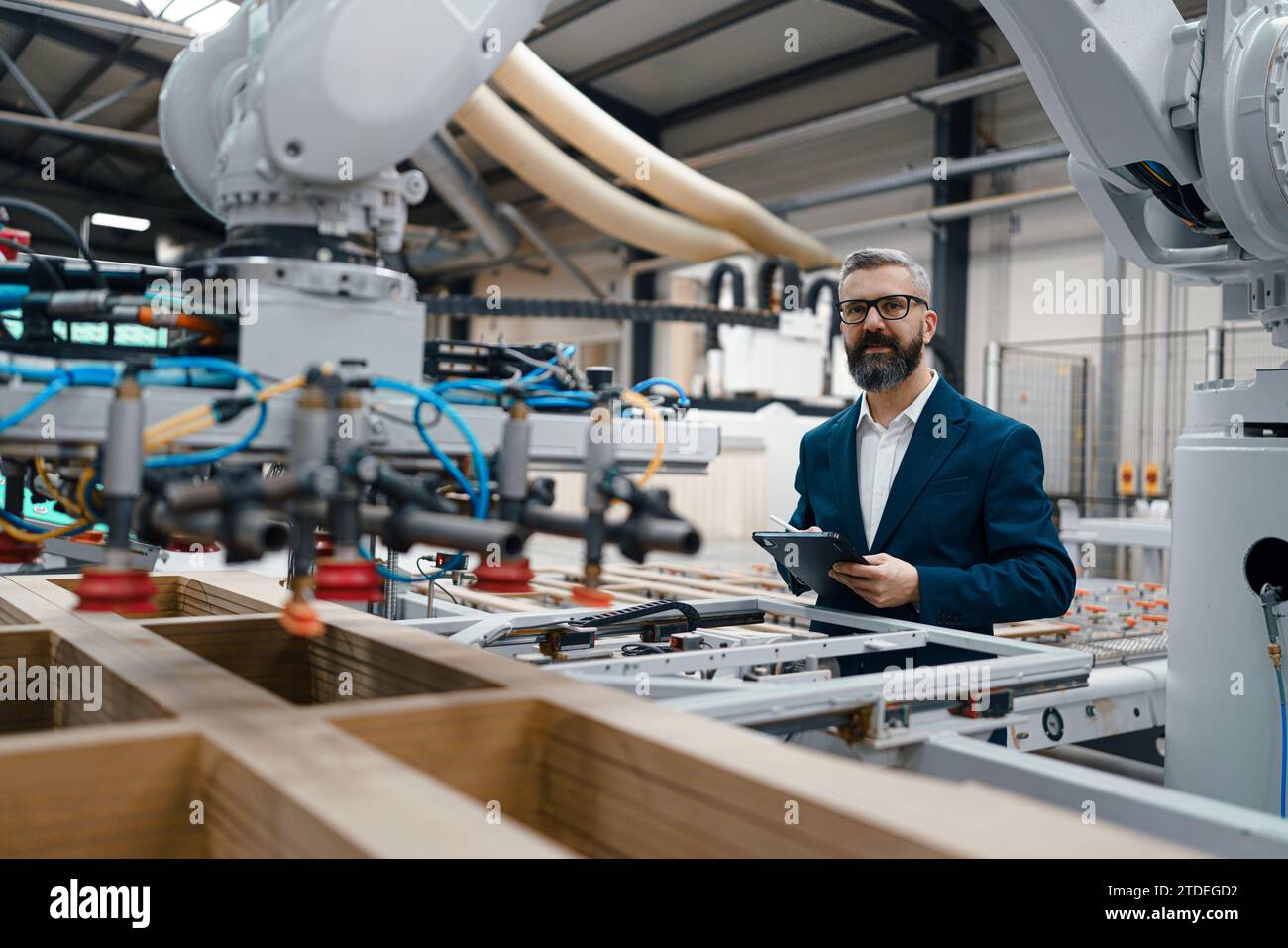 Male engineer in modern industrial factory, checking robotic arm ...