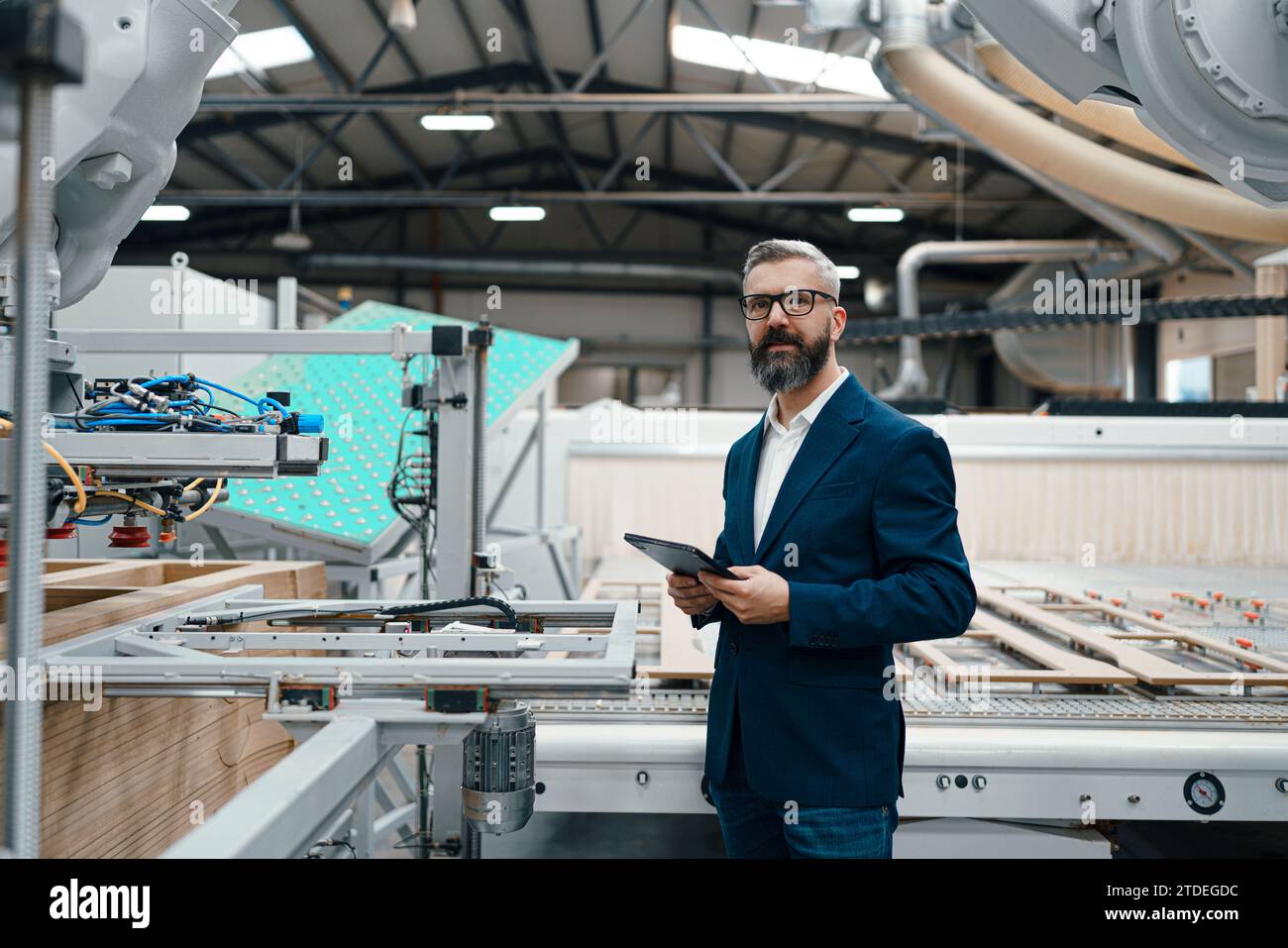 Male engineer in modern industrial factory, checking robotic arm ...