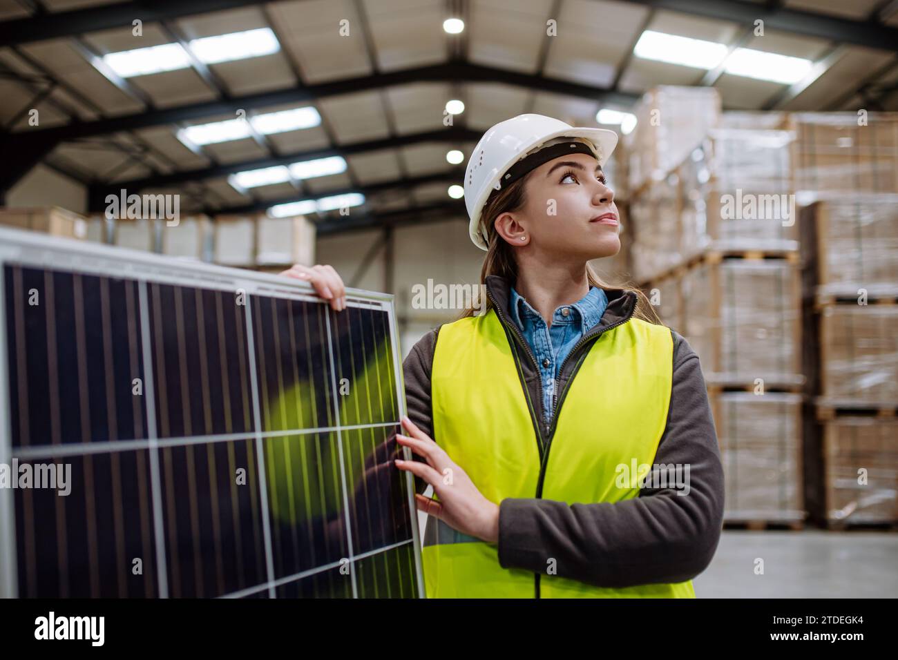 Female worker carrying solar panel in warehouse, factory. Solar panel ...