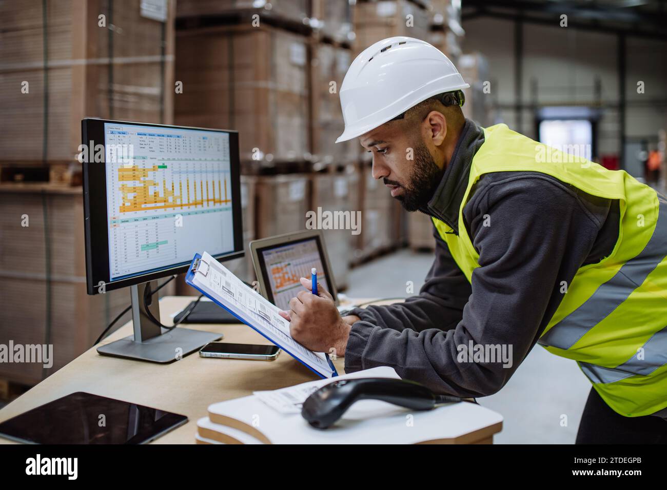 Warehouseman checking delivery, stock in warehouse on computer, pc ...