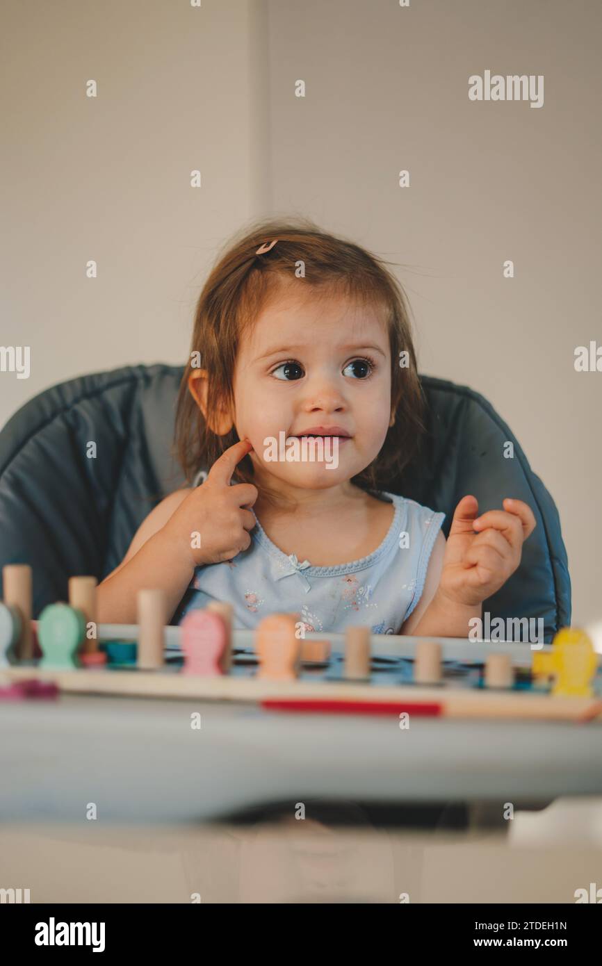 Happy little girl playing with wooden shape sorter toy on the table in ...