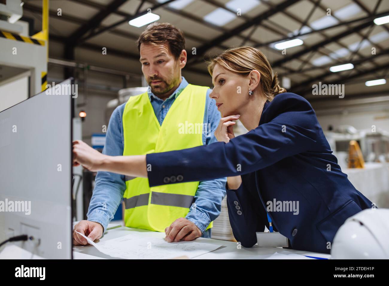 Female engineer reading technical documentation with project manager in ...