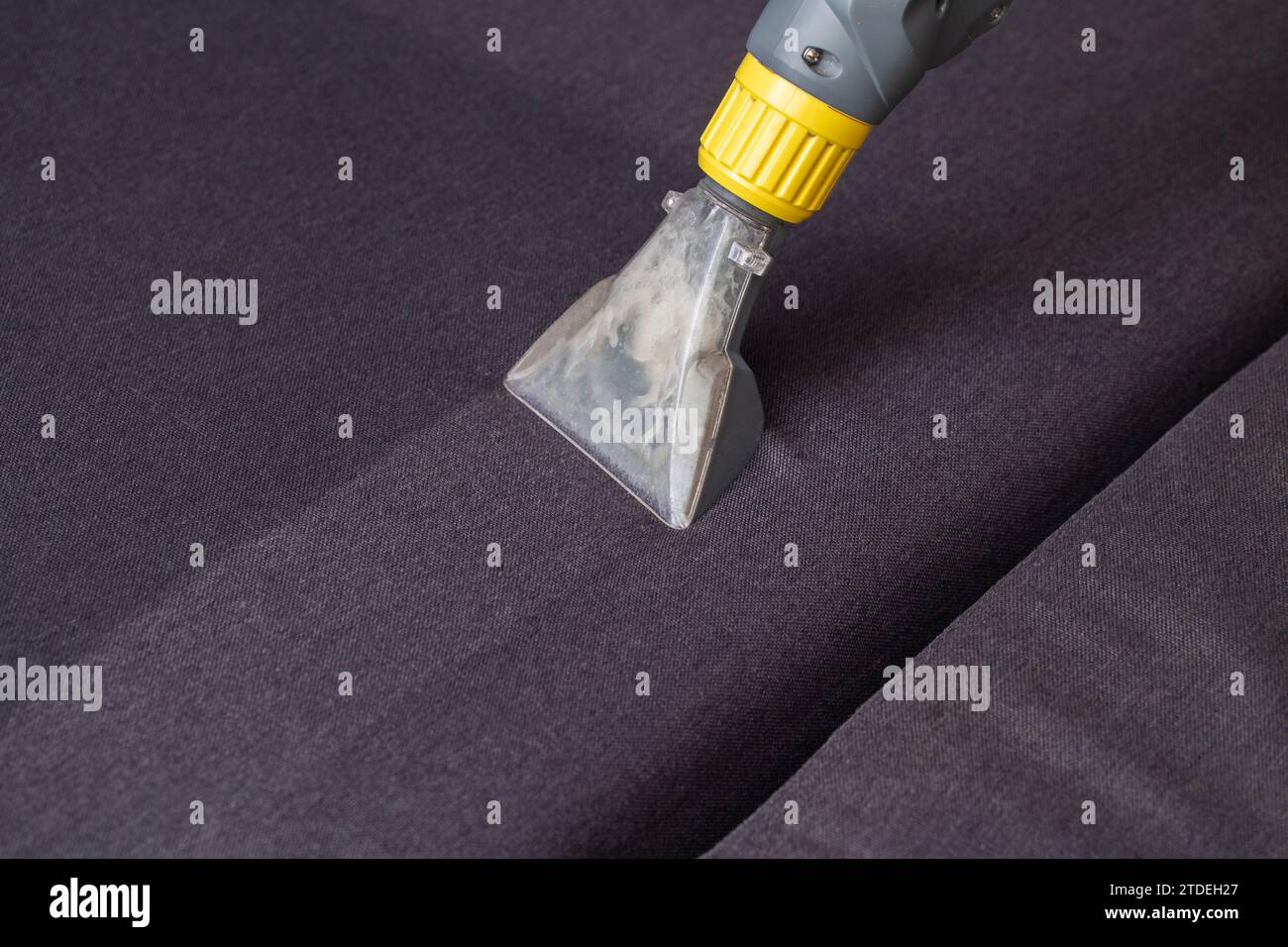 Cleaning the sofa with a special washing vacuum cleaner from dirt. Dry ...