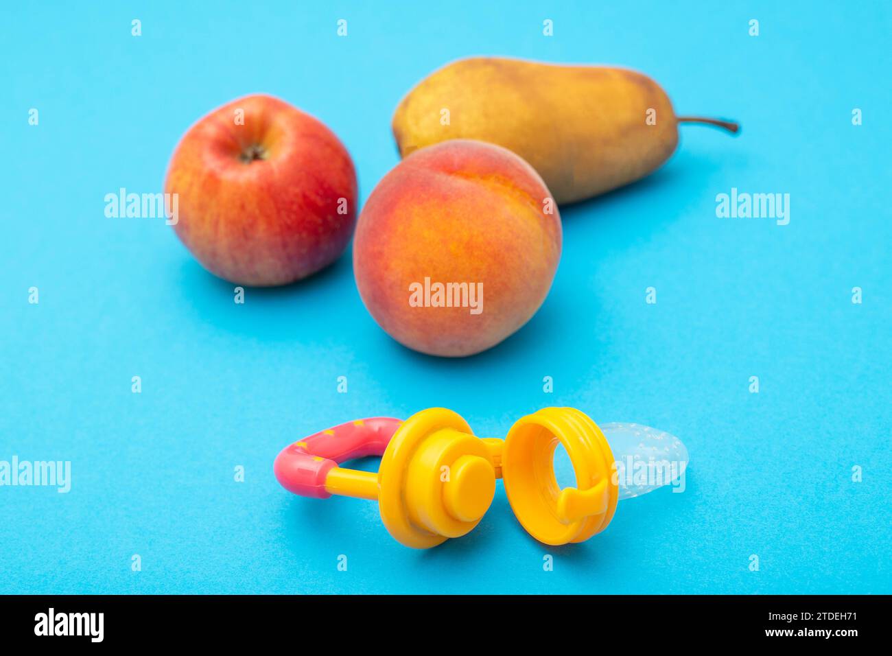 Apple, pear and peach with baby nibbler on a blue background. Concept ...