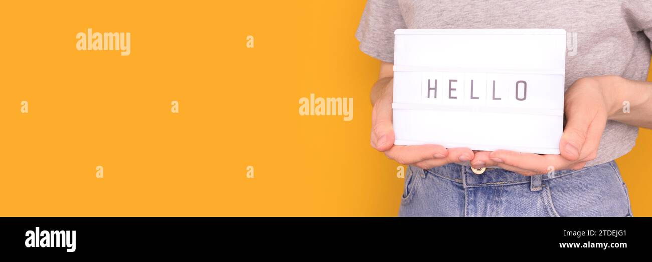 Word Hello. Banner with woman hold in hands lightbox with letters in ...