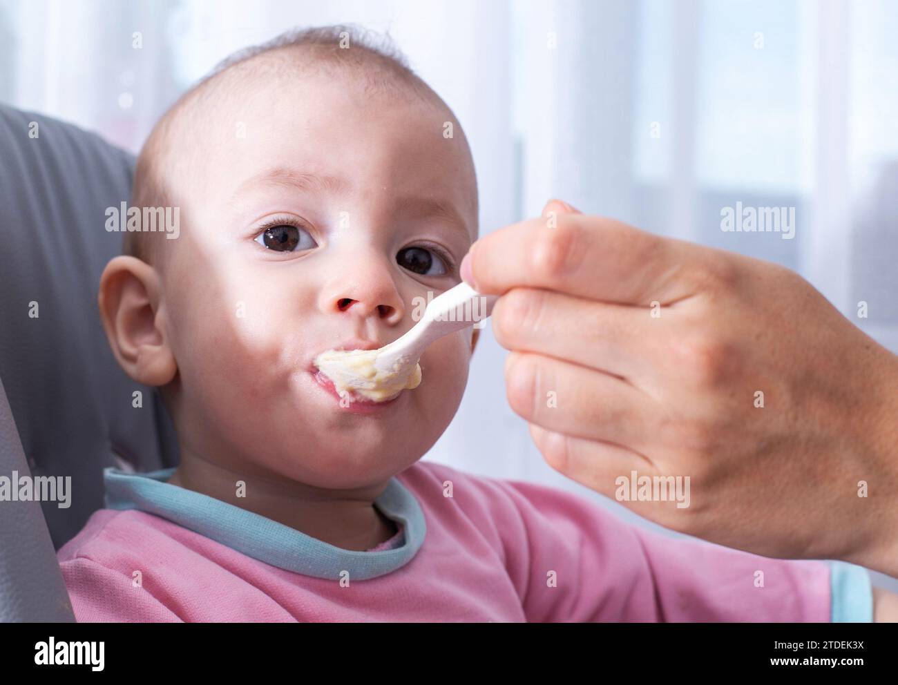 A mother feeds her child, a one-year-old boy, with millet porridge ...
