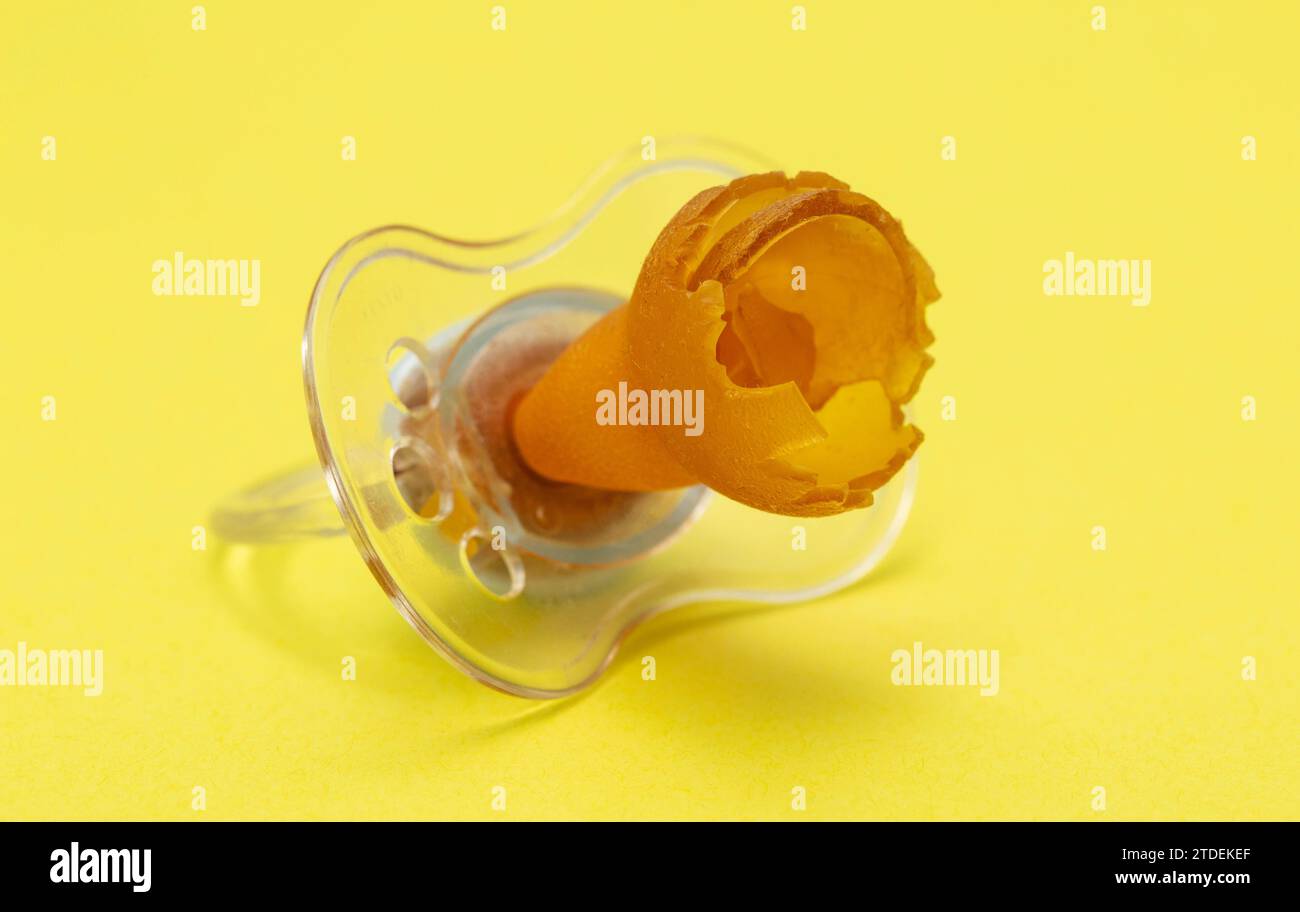 A chewed baby pacifier on a yellow background. Concept of teething in ...