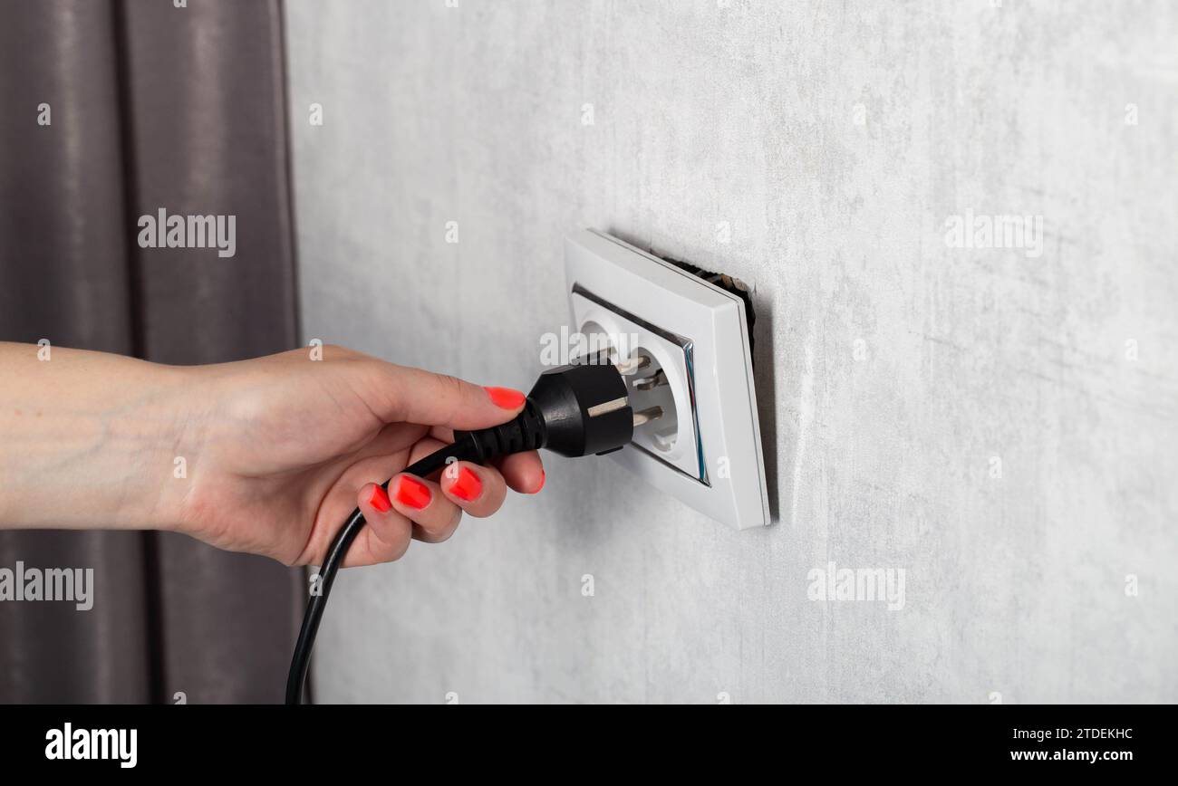 The girl removes the electrical plug from the socket and breaks the ...