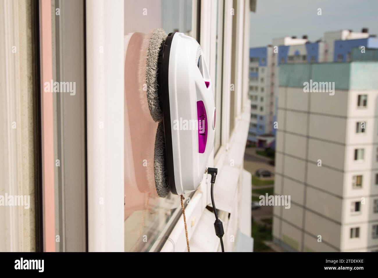 A modern vacuum robot window washer washes glass in an apartment on a ...