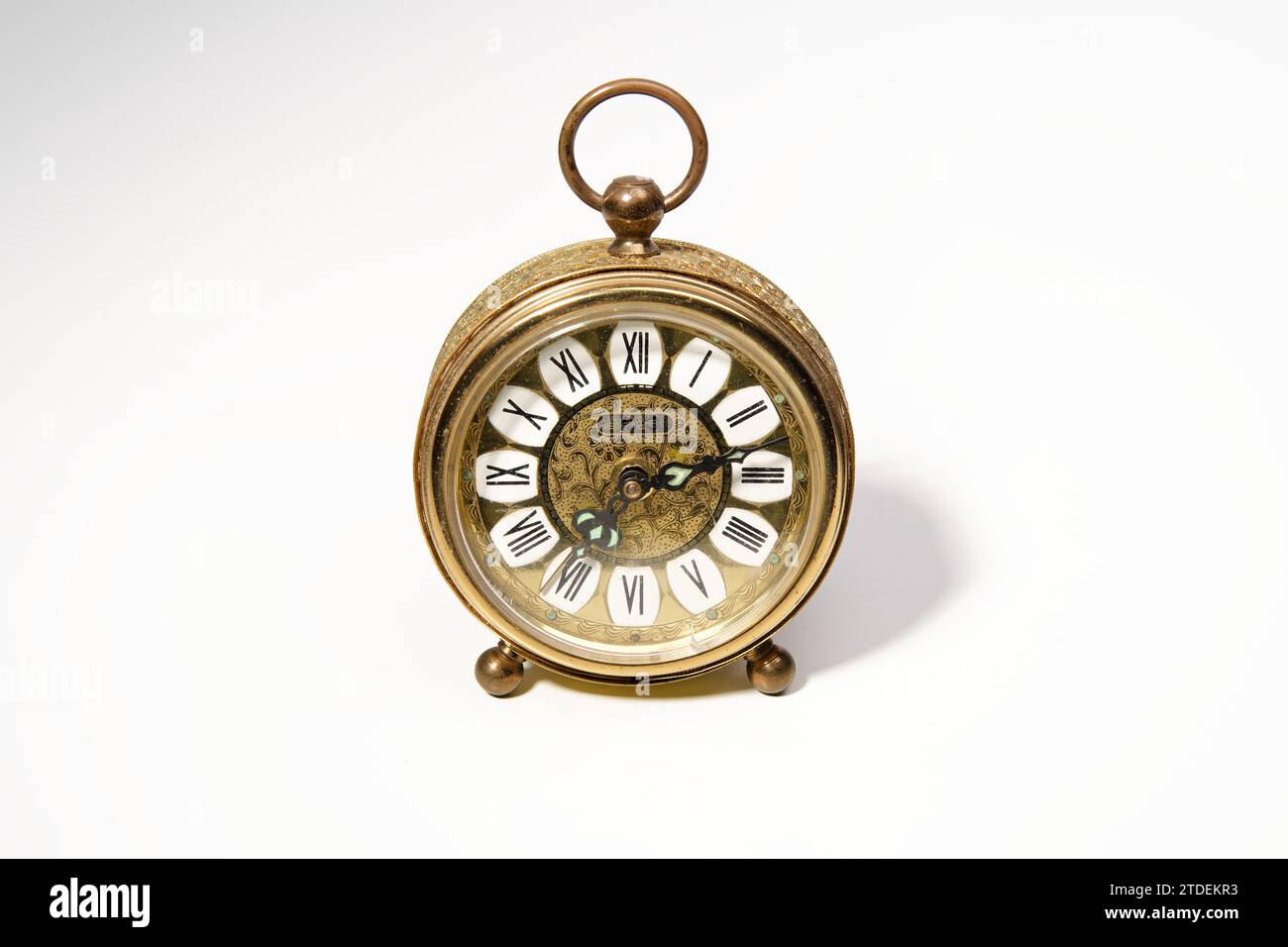 an old golden analog alarm clock with mechanical movement isolated on a ...