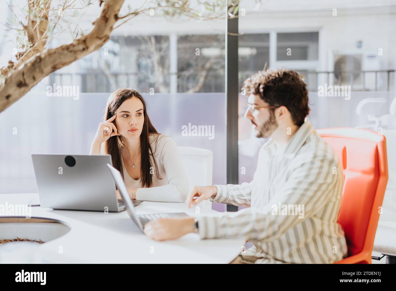 Two coworkers collaborating in an office, discussing project details ...