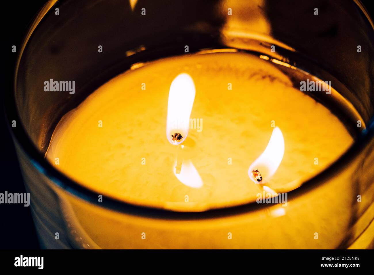 Close-up on light aromatic candle with two wicks in glass with melted ...