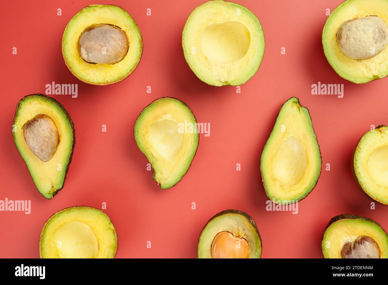Cut fresh ripe avocados on red background Stock Photo - Alamy