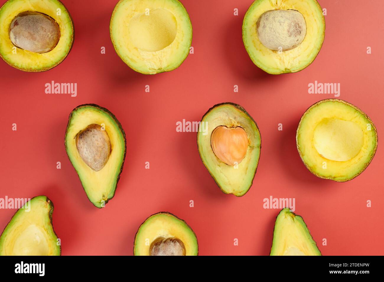 Red background with cut avocados Stock Photo - Alamy