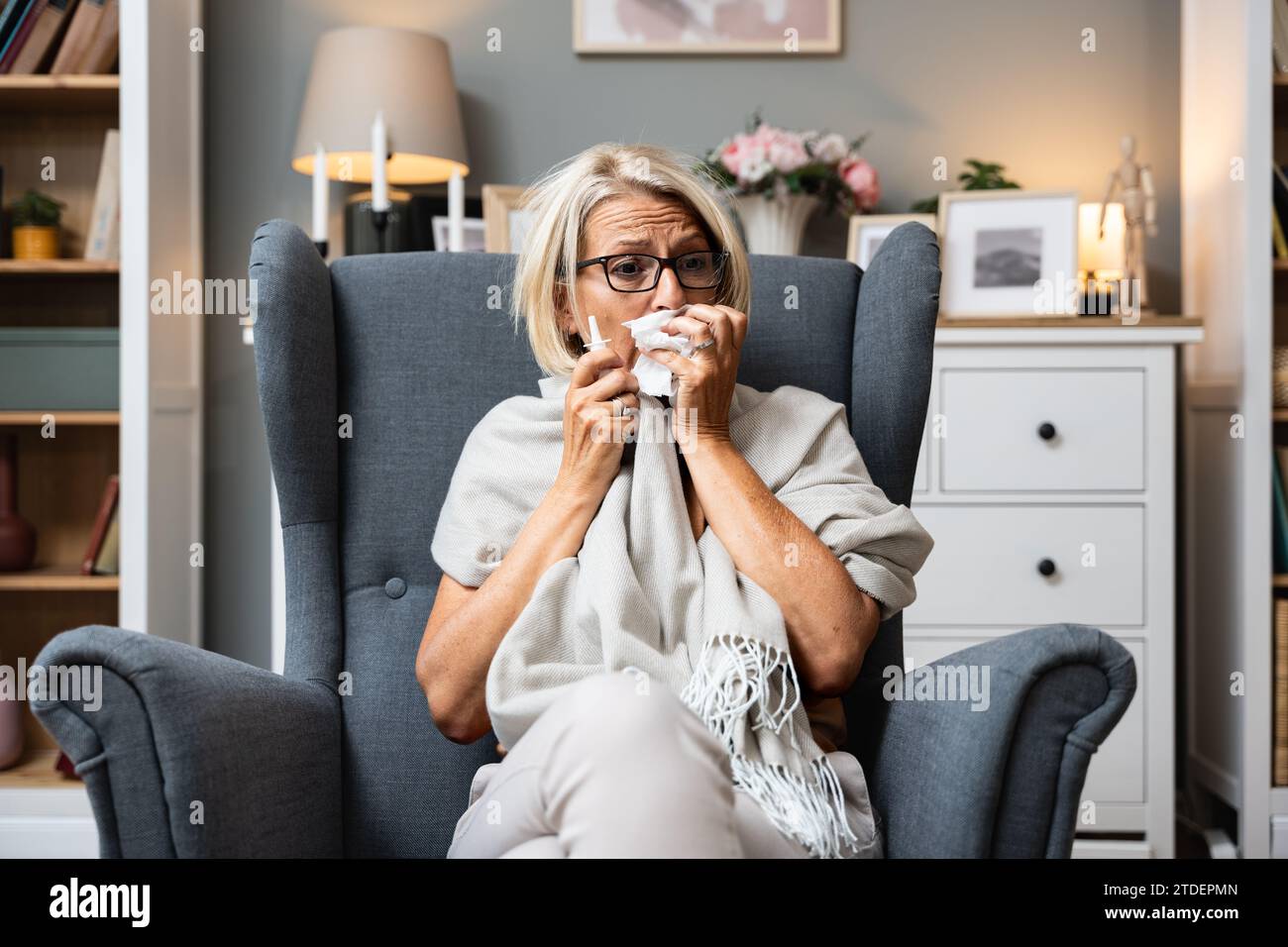 Senior woman sick and blowing nose at home from virus, allergy and ...