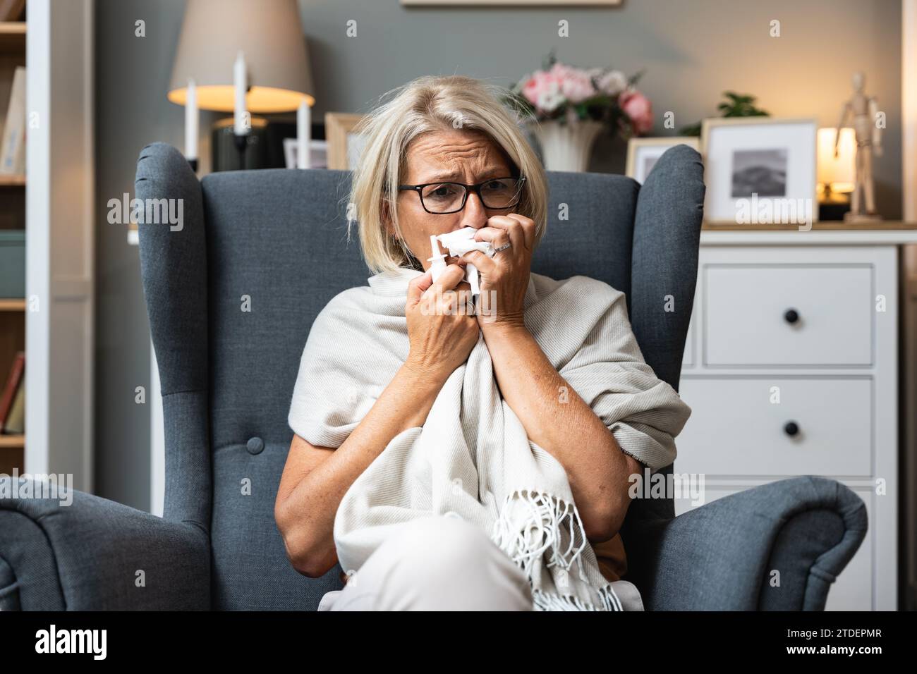 Senior woman sick and blowing nose at home from virus, allergy and ...