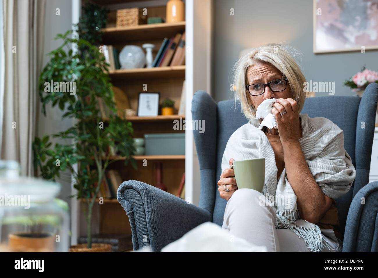 Senior woman sick and blowing nose at home from virus, allergy and ...