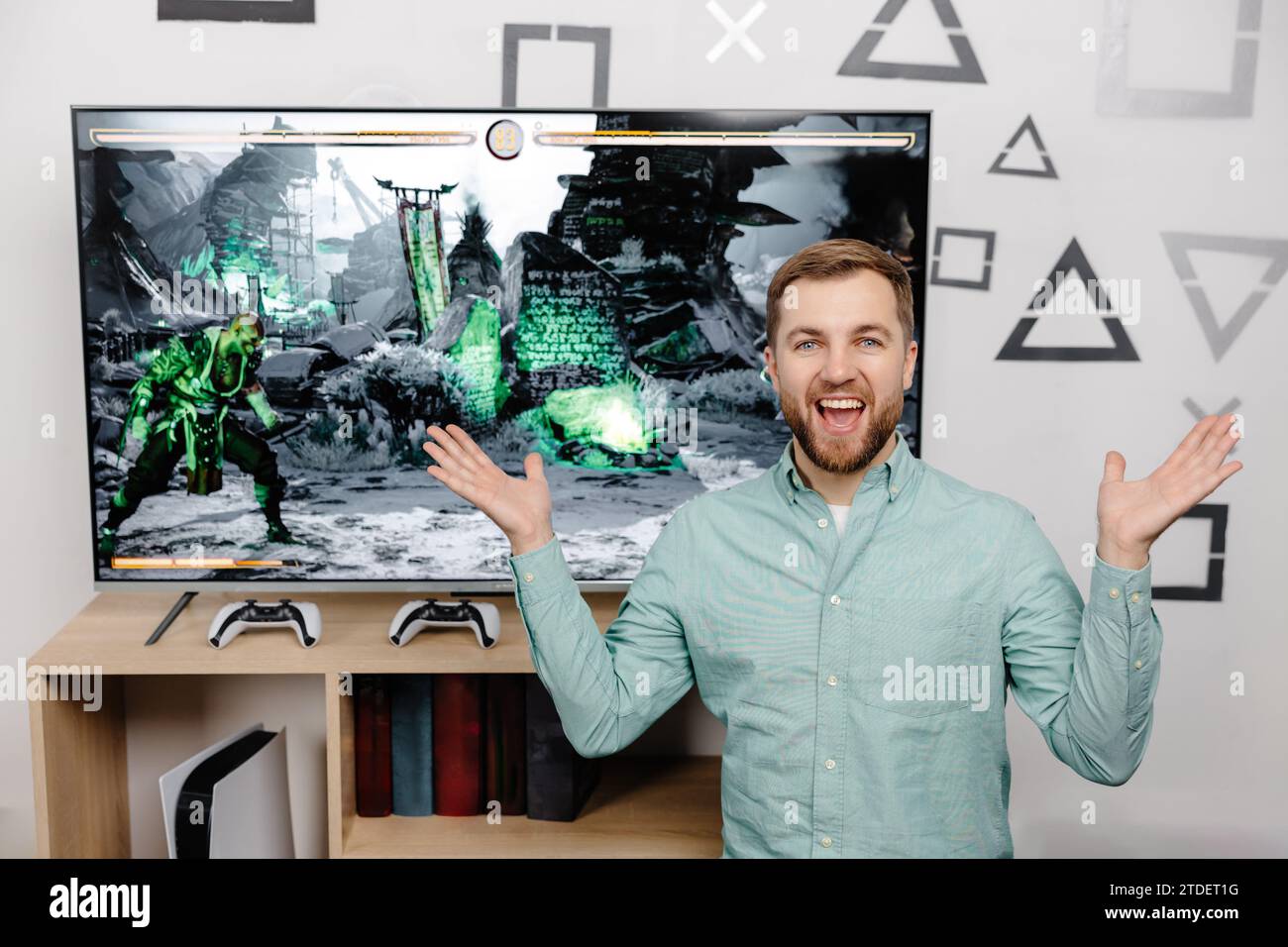 Young bearded man standing at the wall in the room and playing, holding ...