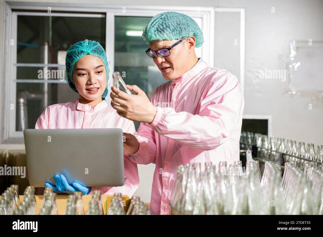 Two engineers oversee quality control checking product bottles on a ...