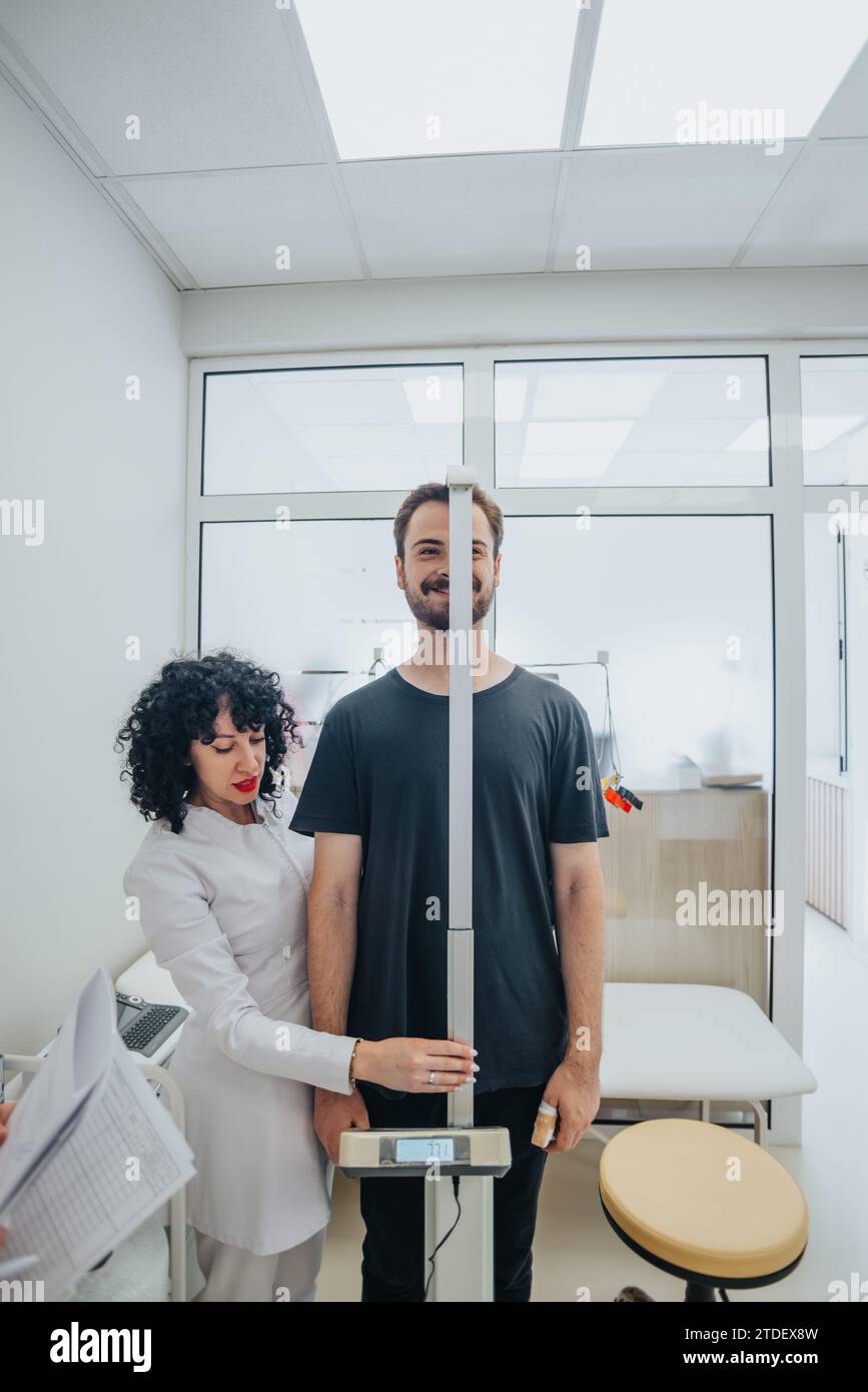 Medical professional in an office measuring patient height in a ...