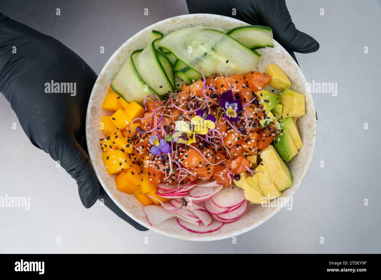 an image overlooking a chef presenting a freshly prepared salmon poke ...
