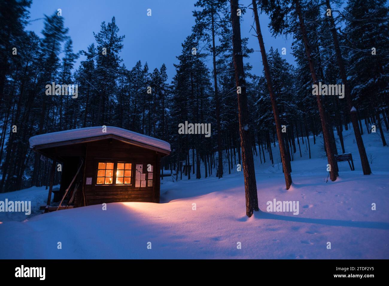 Log cabin with fire inside, winter, Lemmenjoki National Park, Finland ...