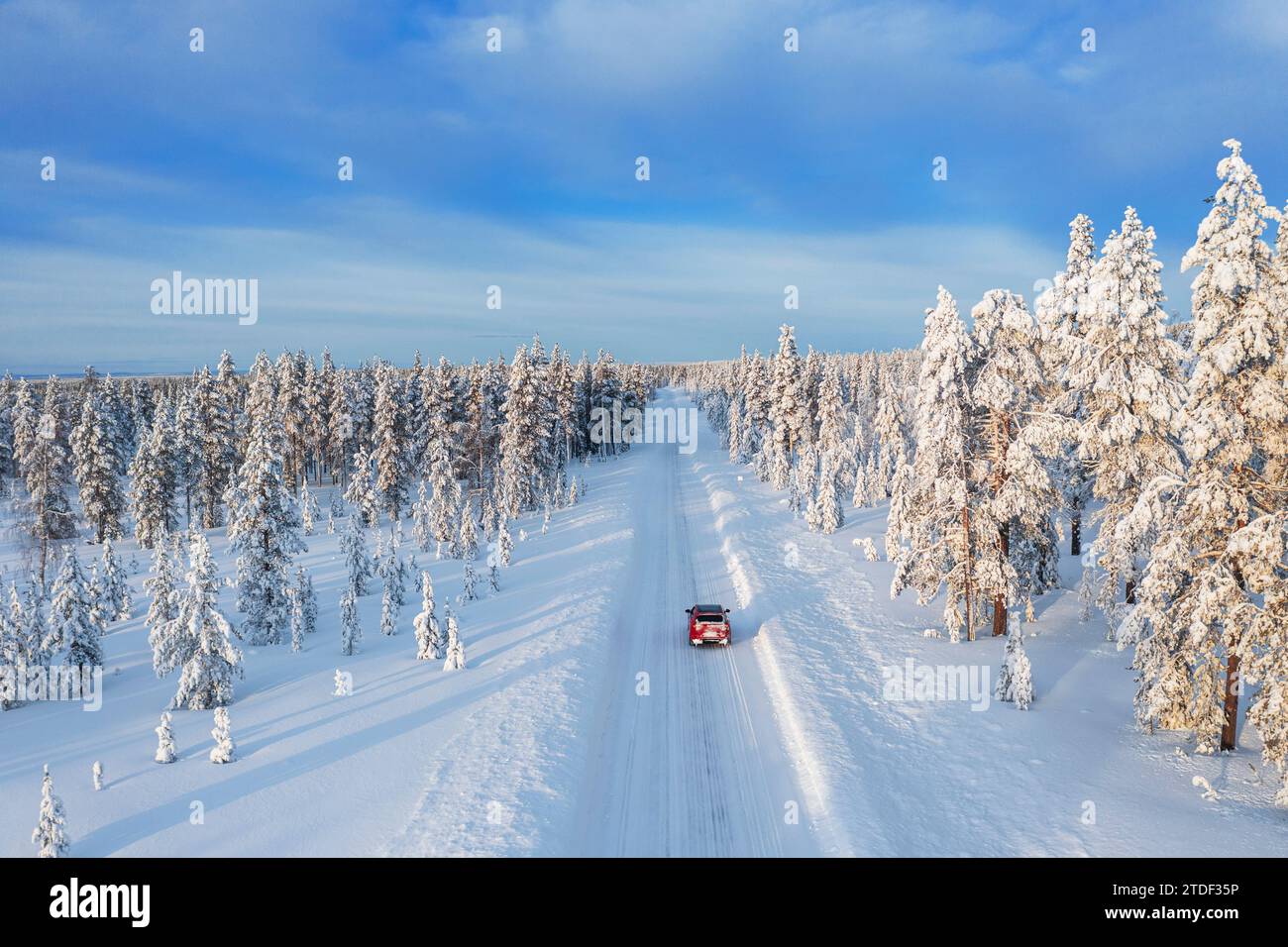 Drone view of a car driving on an empty and frozen road in the white ...
