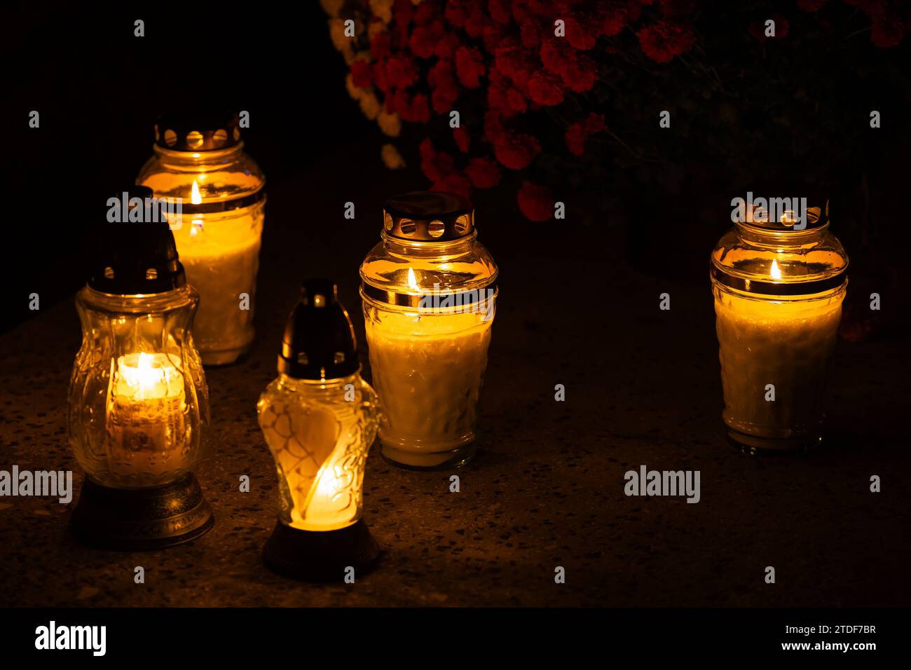 Night shot of the flames of glass cemetery candles standing on ...