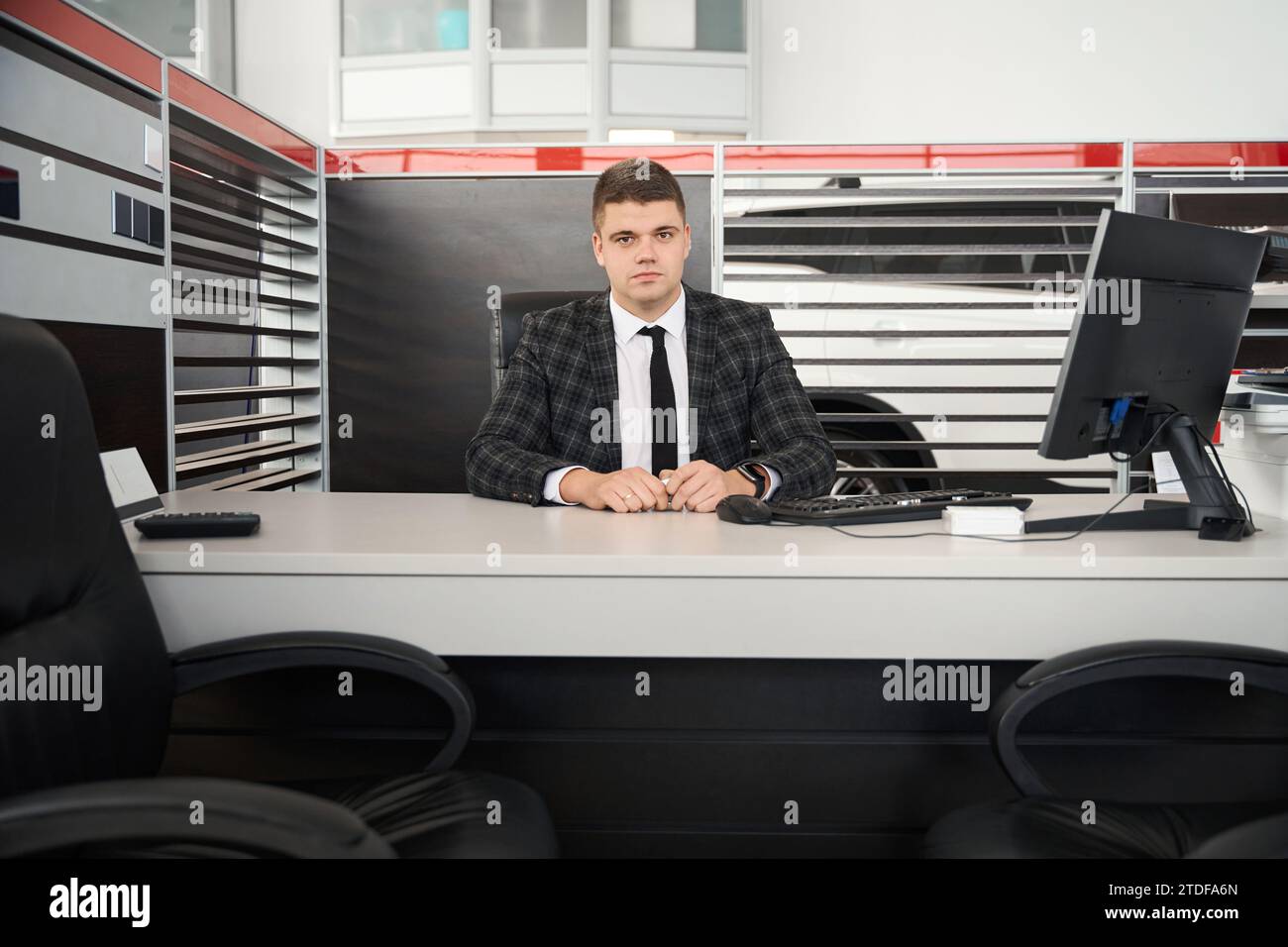 Salesman in auto salon sitting at his workplace in office waiting for ...