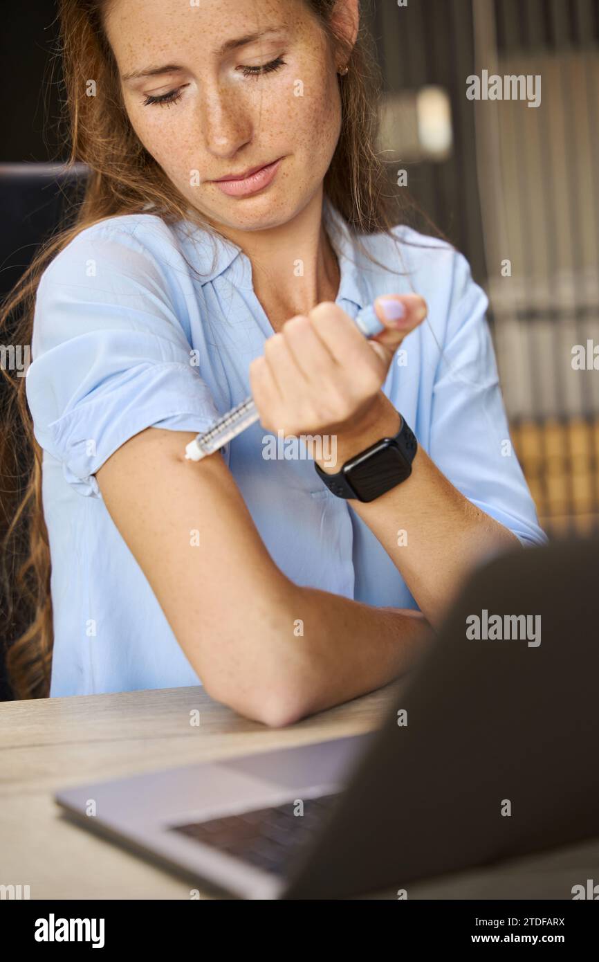 Young caucasian sick businesswoman taking injection with syringe in ...
