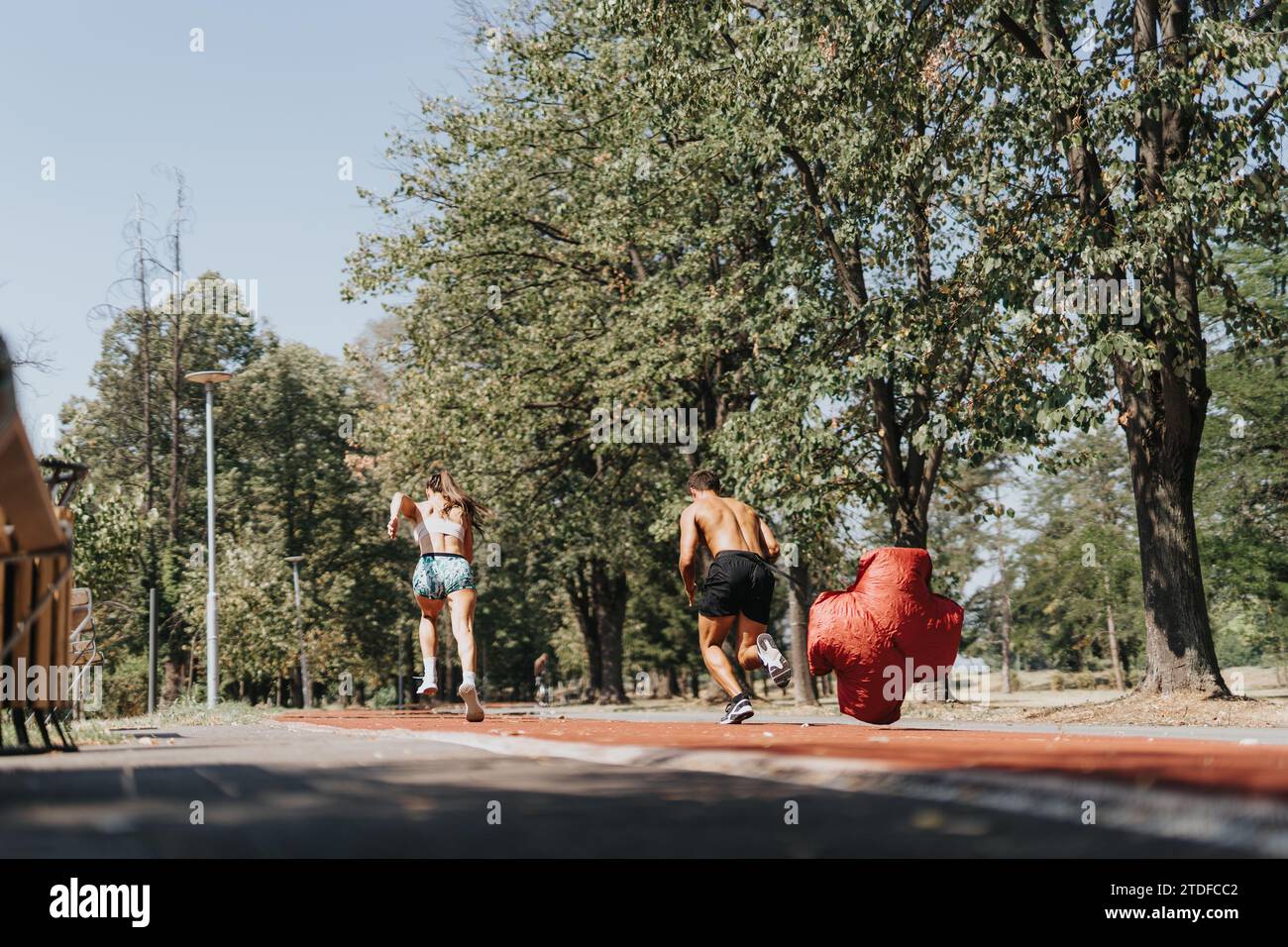 Caucasian athletes running with a parachute, enjoying outdoor training ...
