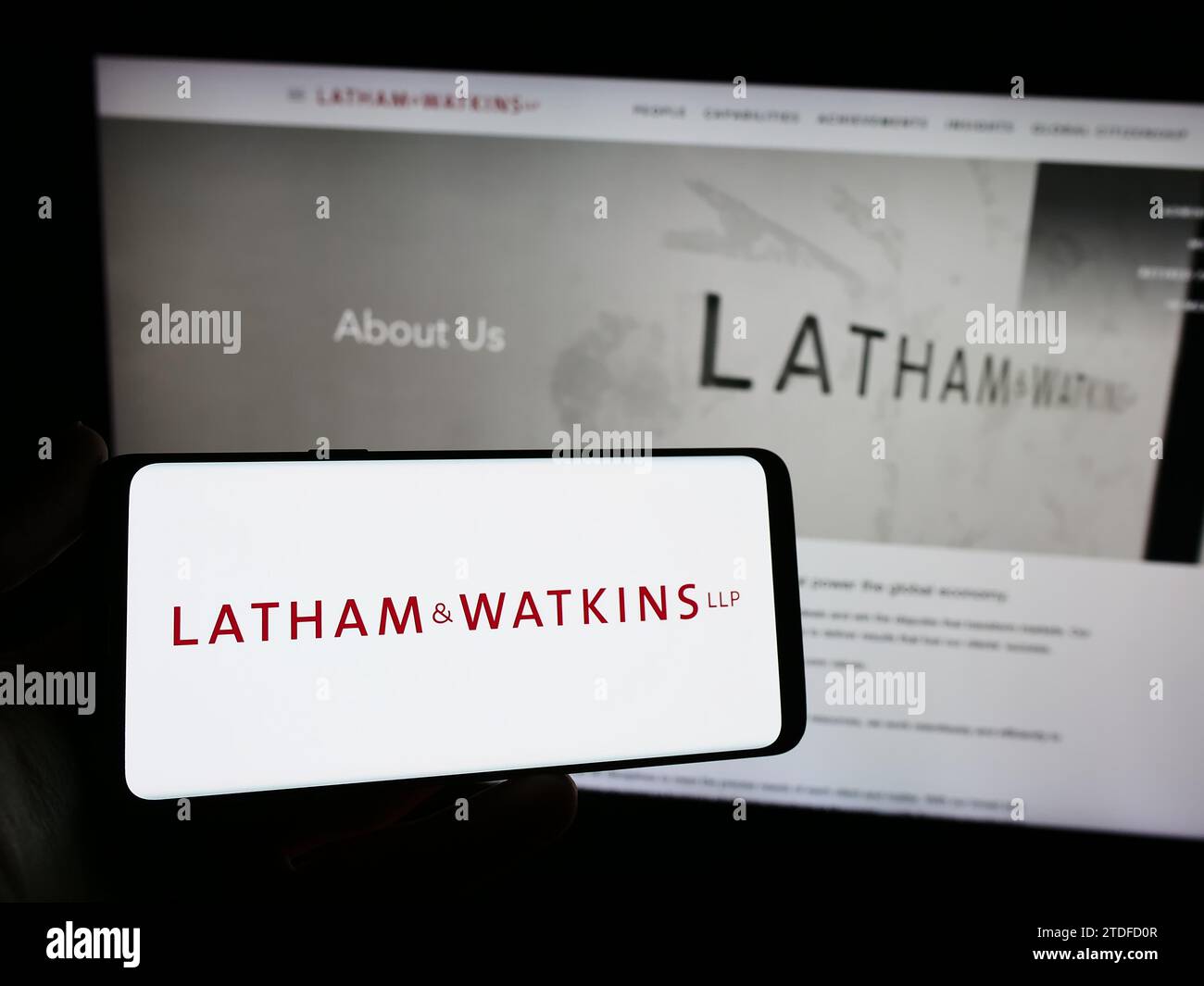 Person holding smartphone with logo of US law firm Latham and Watkins LLP (LW) in front of ...