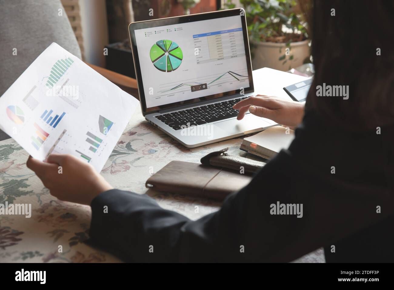 Woman doing financial analysis with a laptop at the window of a cafe ...