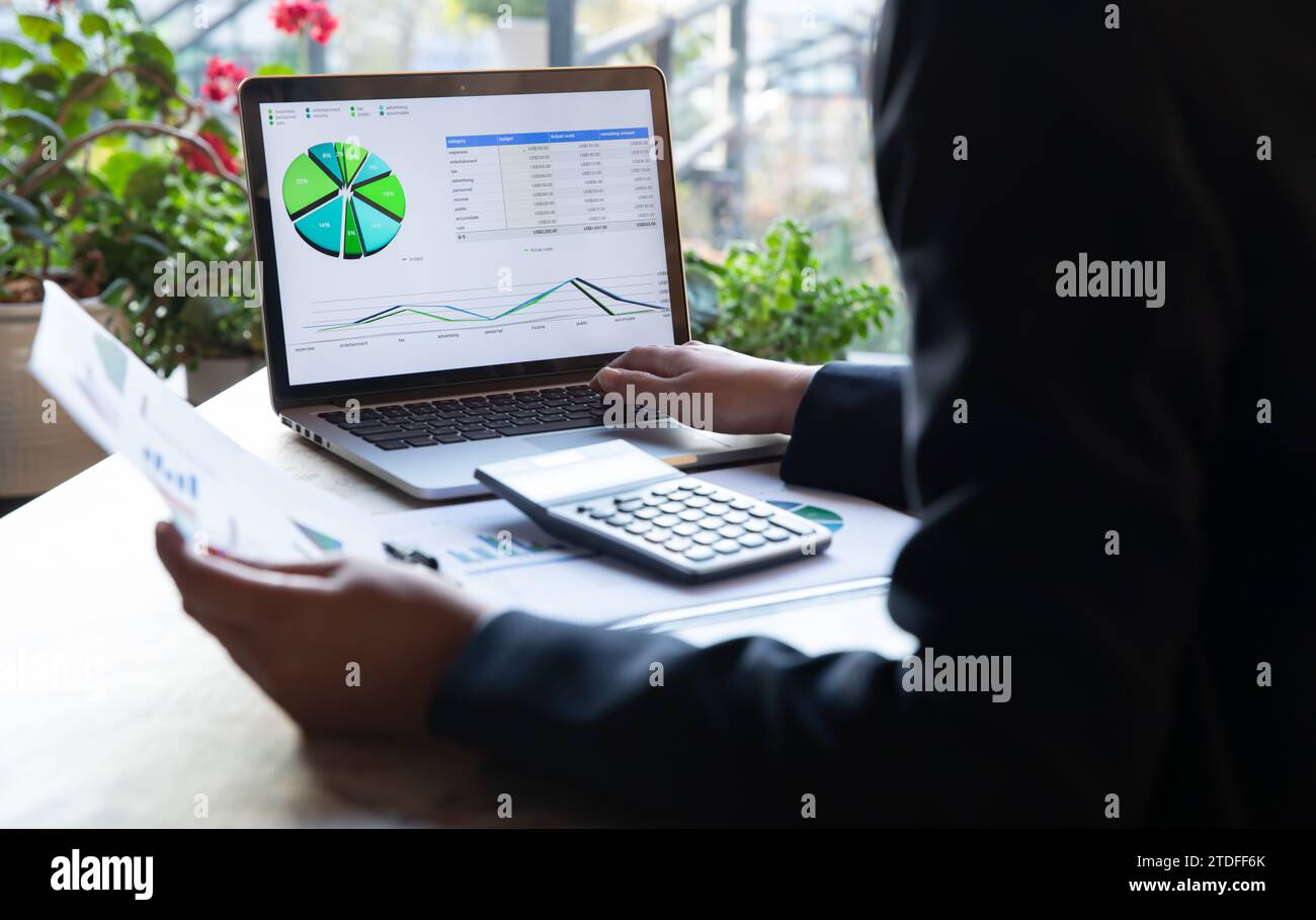 Woman doing financial analysis with a laptop at the window of a cafe ...