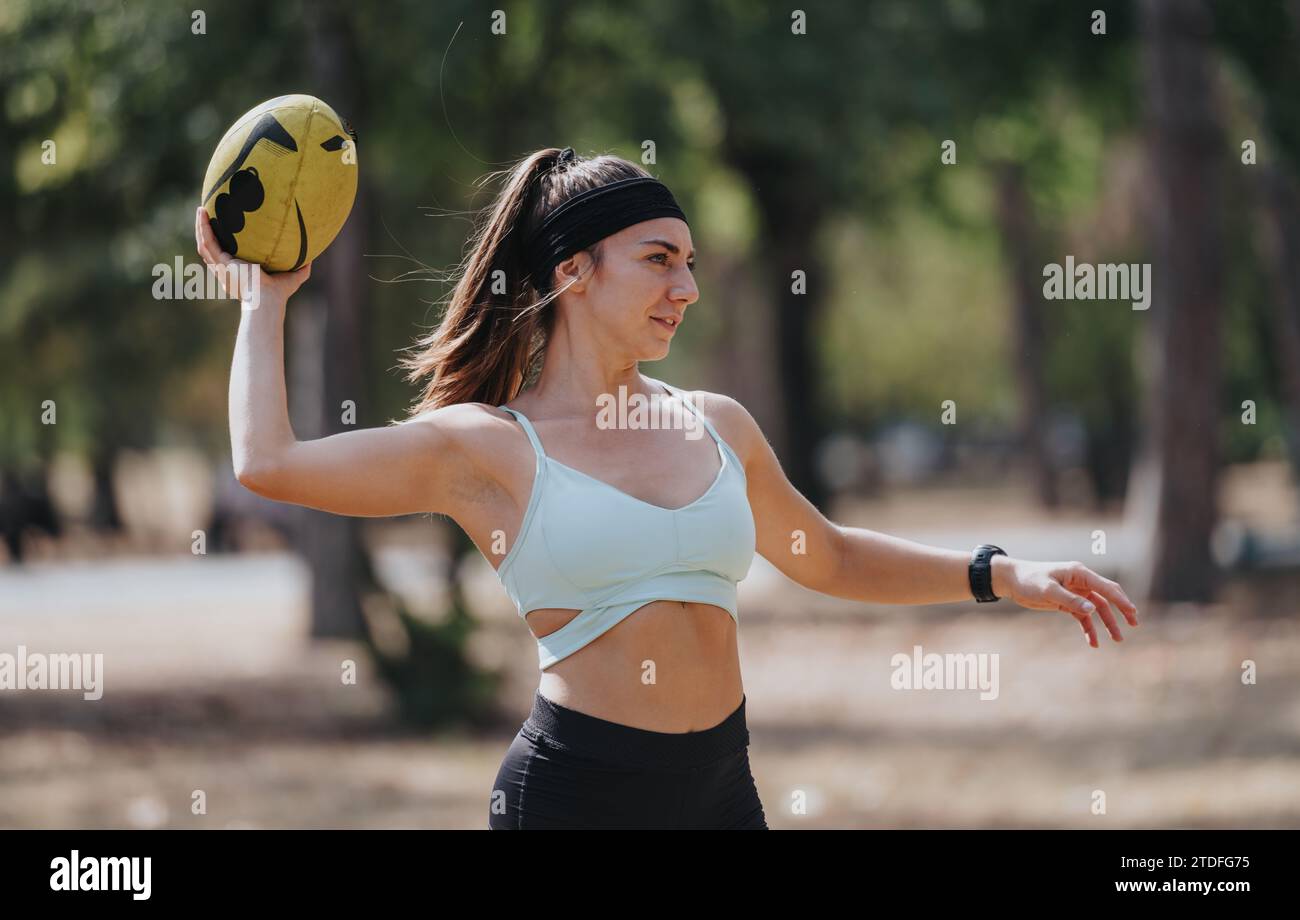 Active girl having fun throwing a ball in the park, surrounded by ...