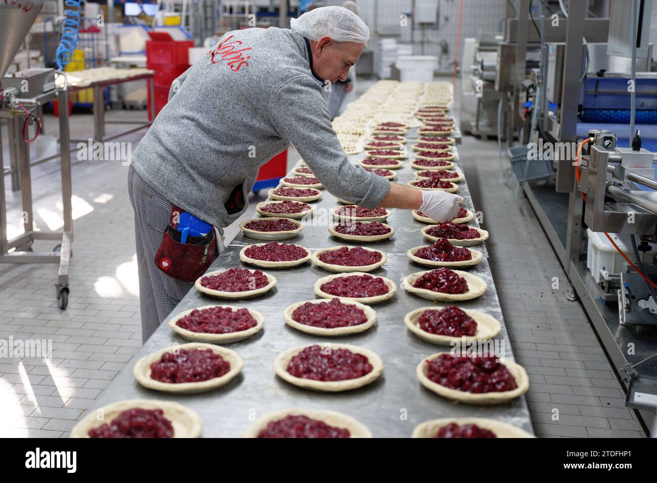 Aachen, Germany. 18th Dec, 2023. An employee works on cakes at the ...