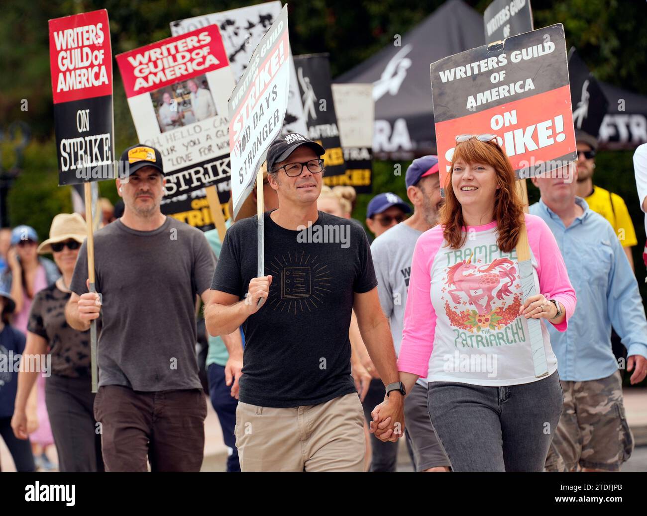 Striking Writers Guild of America member Corey Evett, center, and his ...
