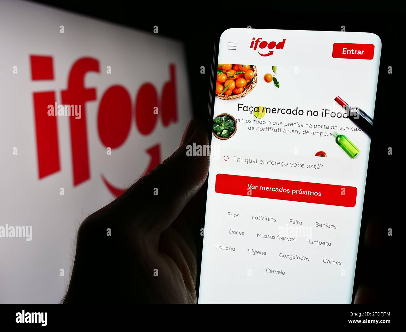 Person holding smartphone with webpage of Brazilian food ordering and delivery company iFood in ...