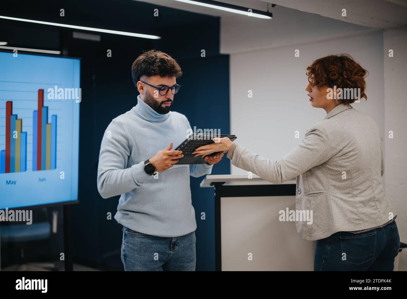 Young business people analyzing statistics on a TV screen ...