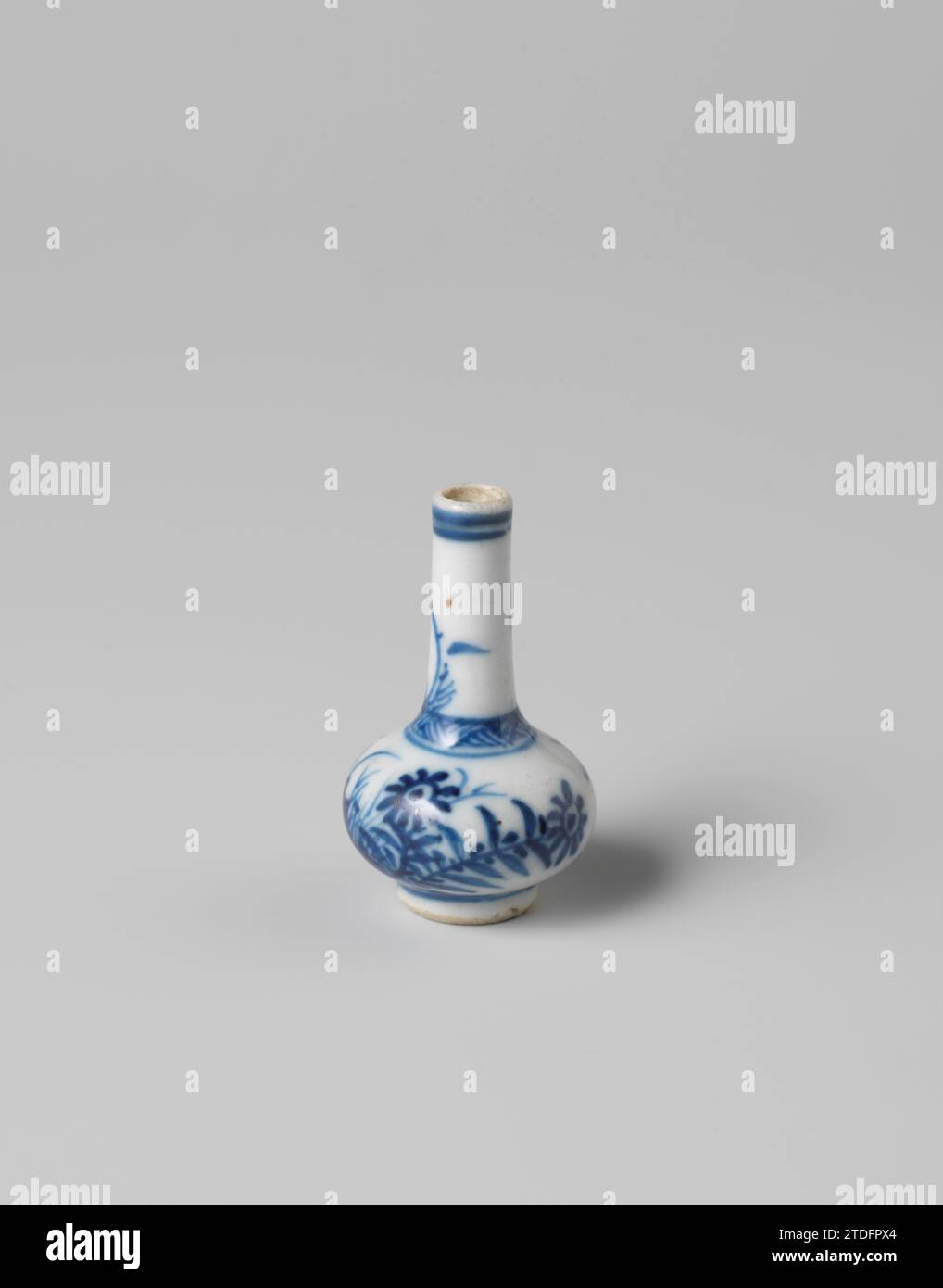 Miniature bottle vase with flowering plants and an insect near a rock ...