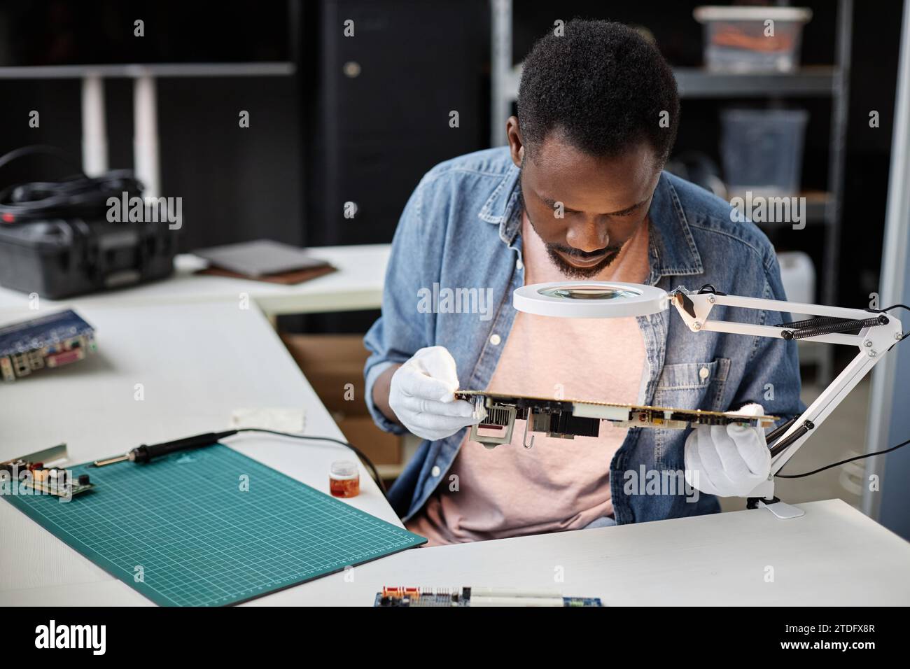 Front view at African American man inspecting circuit board with ...