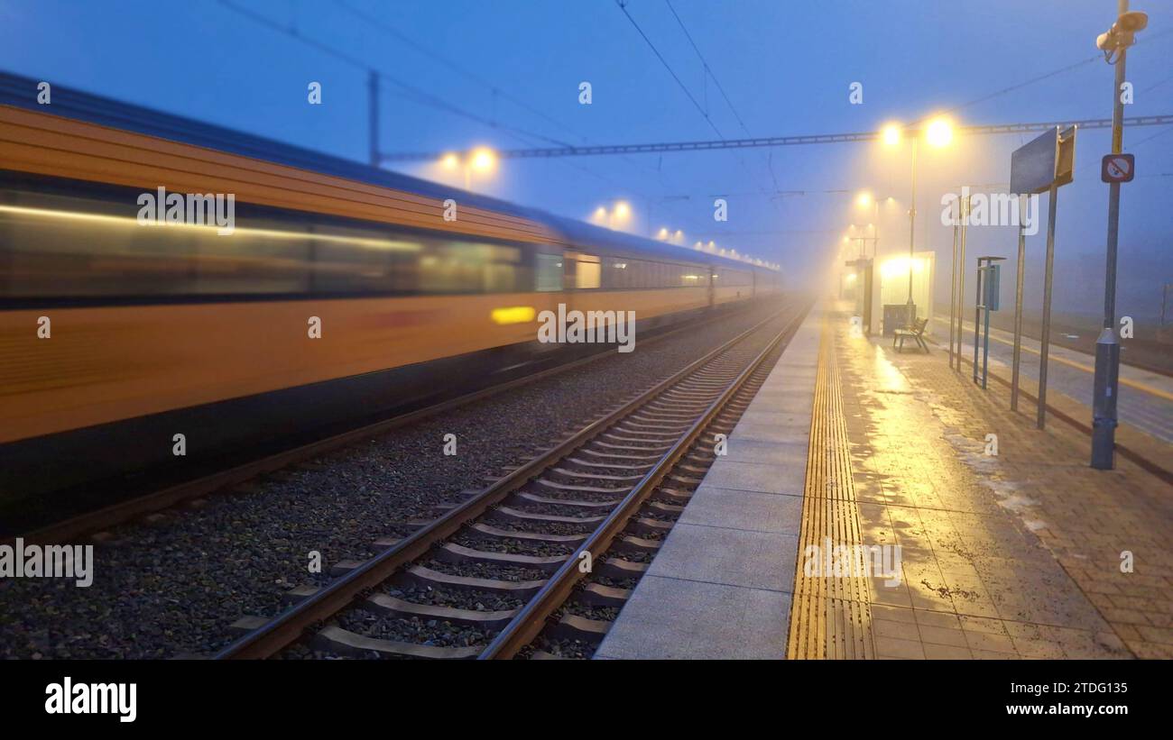 A passenger train entering the station in the fog. Night train passing the station. The concept ...