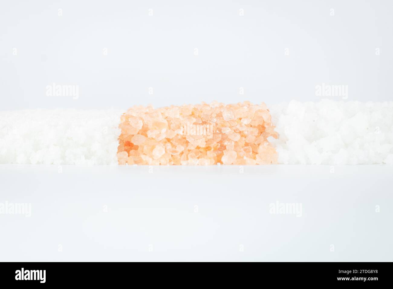 table salt and pink salt and white salt crystals lined up on white ...
