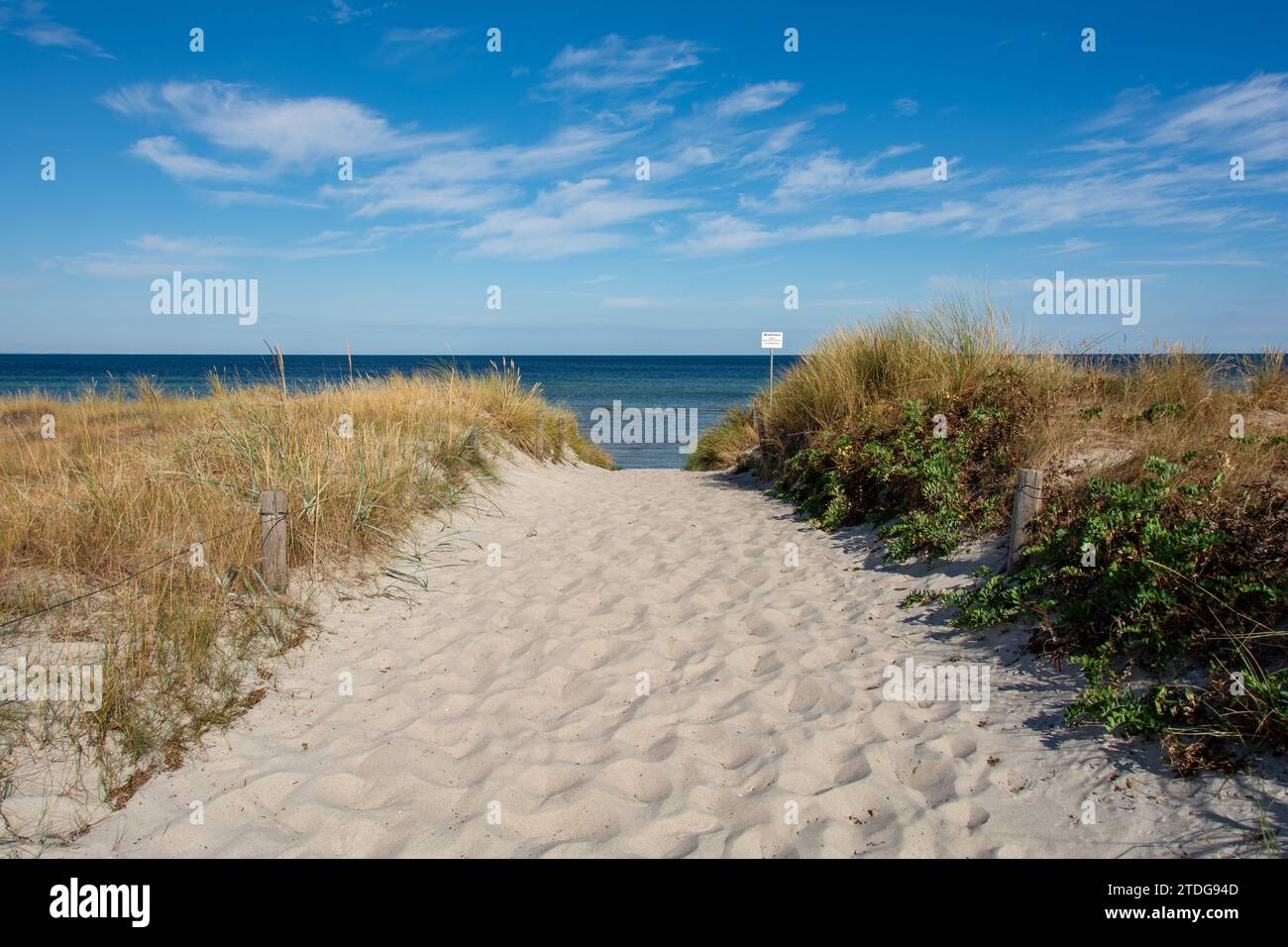 Path between the sand dunes overlooking the sea with blue sky. With ...