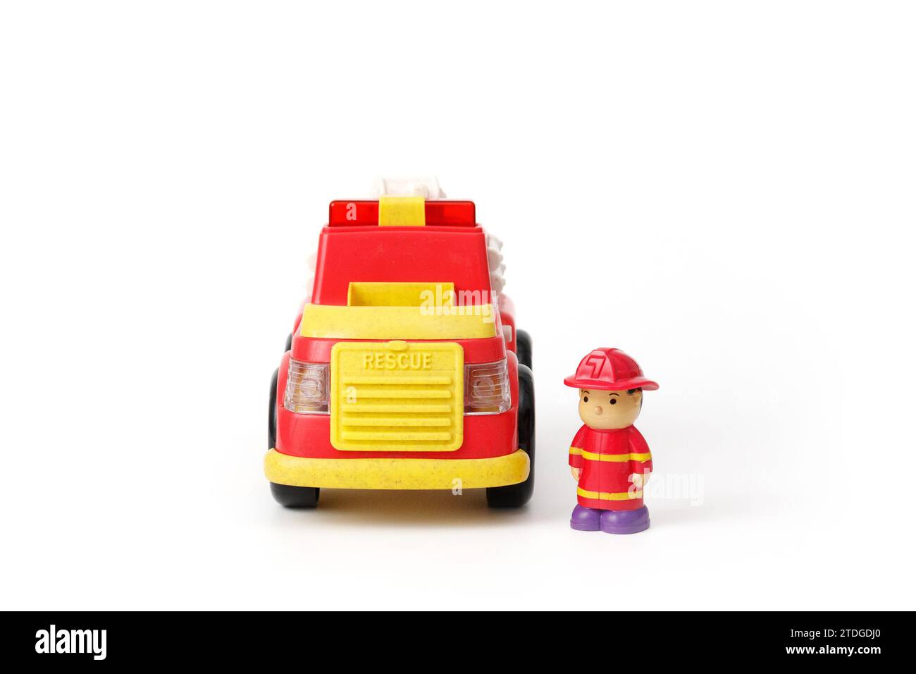 Children's toy red fire truck with a fireman in uniform standing next ...
