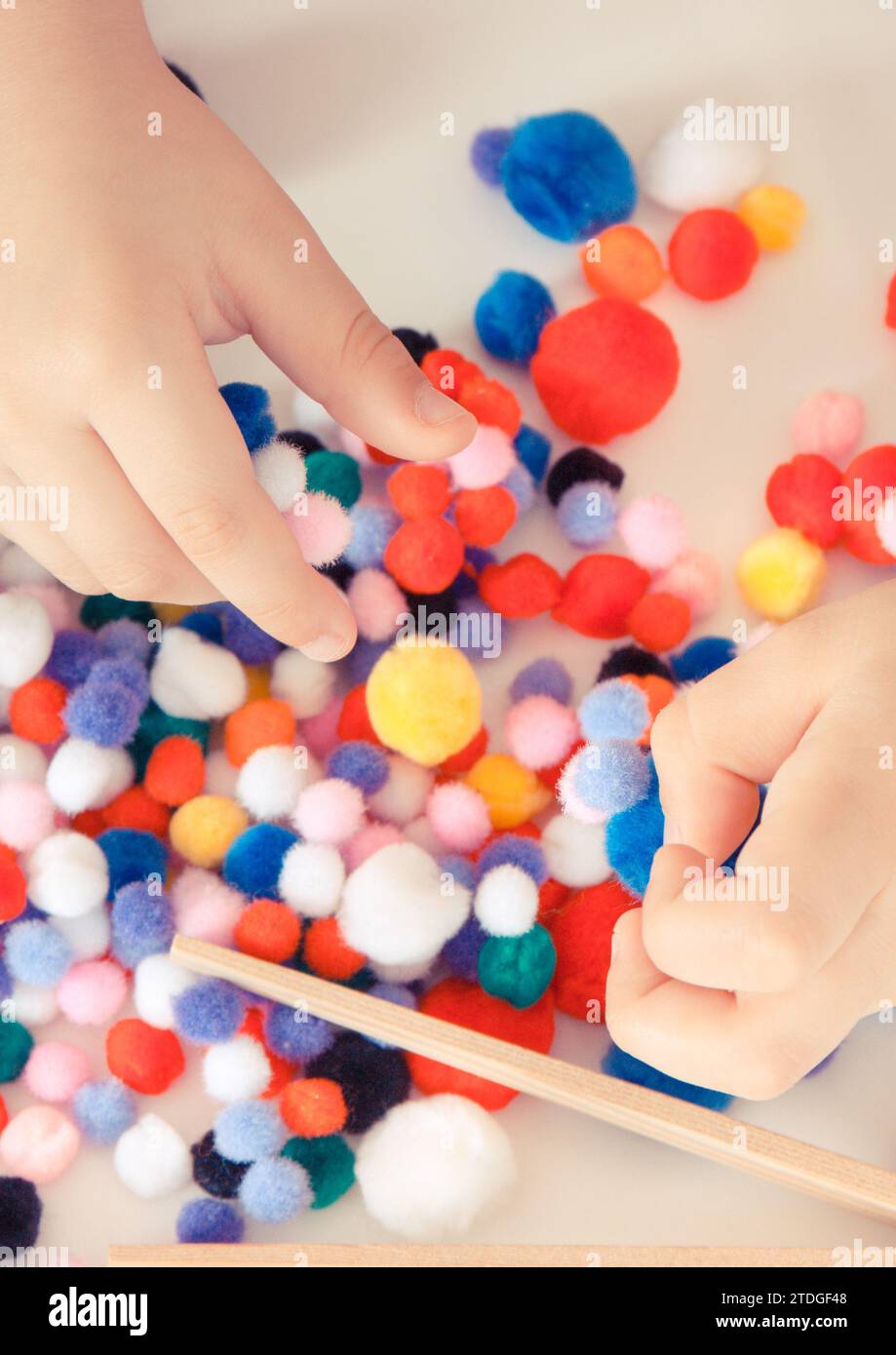 Preschooler playing with small colorful pompoms. Development of kids ...