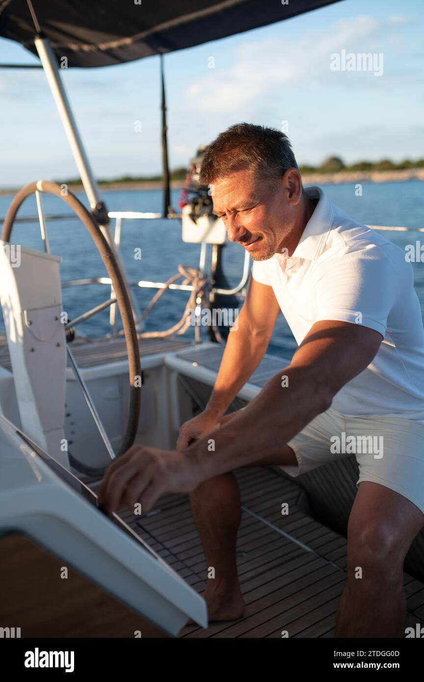 Man in white clothes sailing on a yacht Stock Photo - Alamy